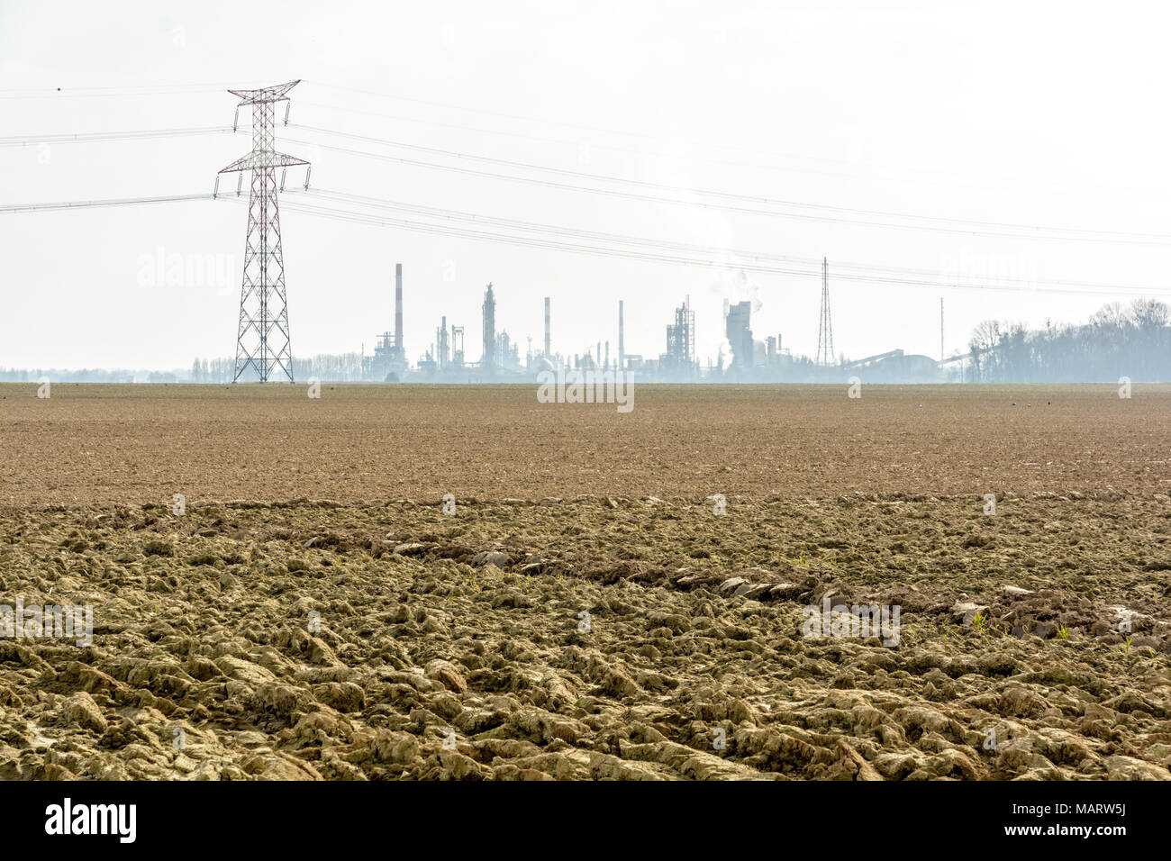A plowed land with a transmission tower, a high-voltage power line and ...