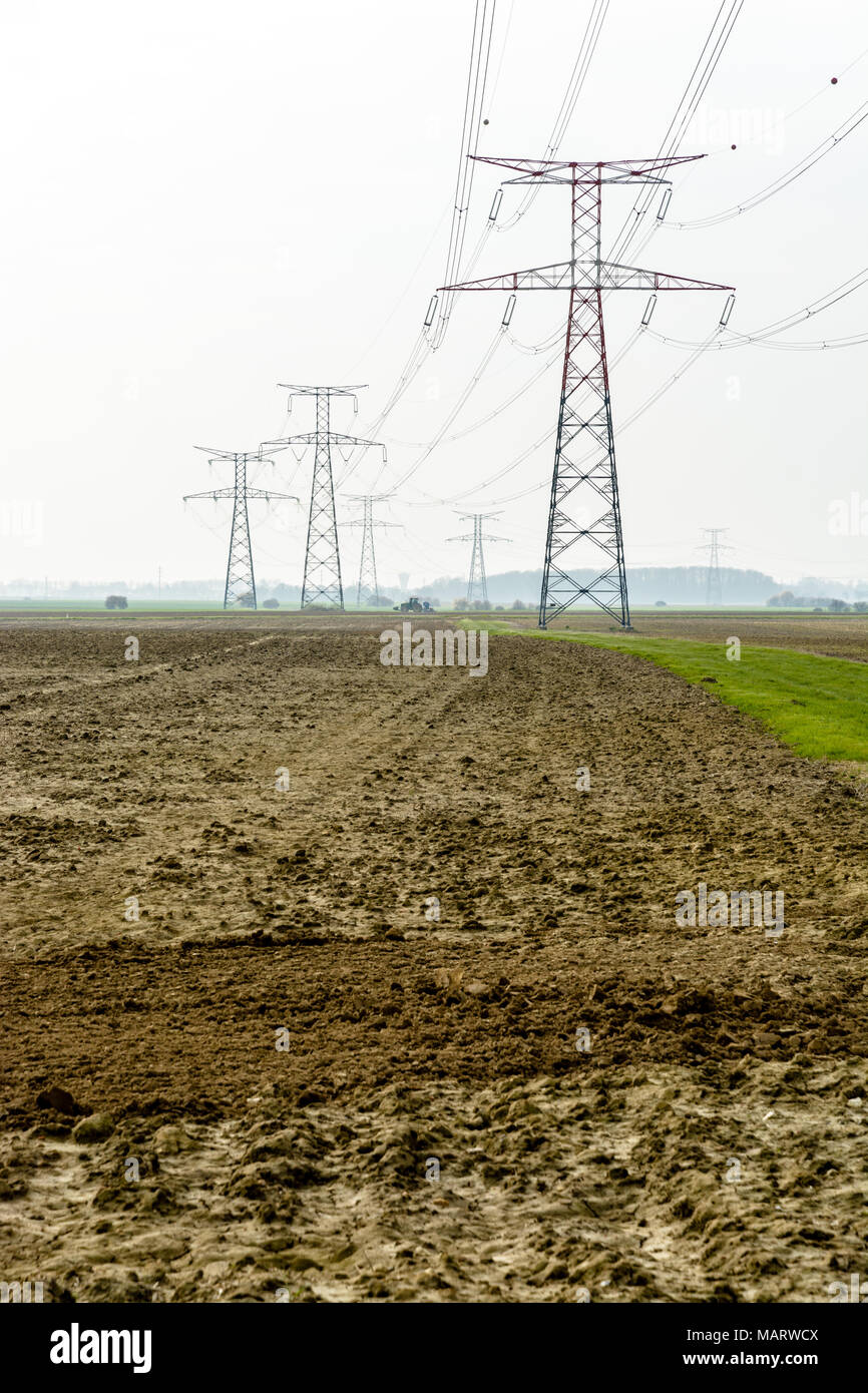 A row of transmission towers supporting a high-voltage overhead power ...