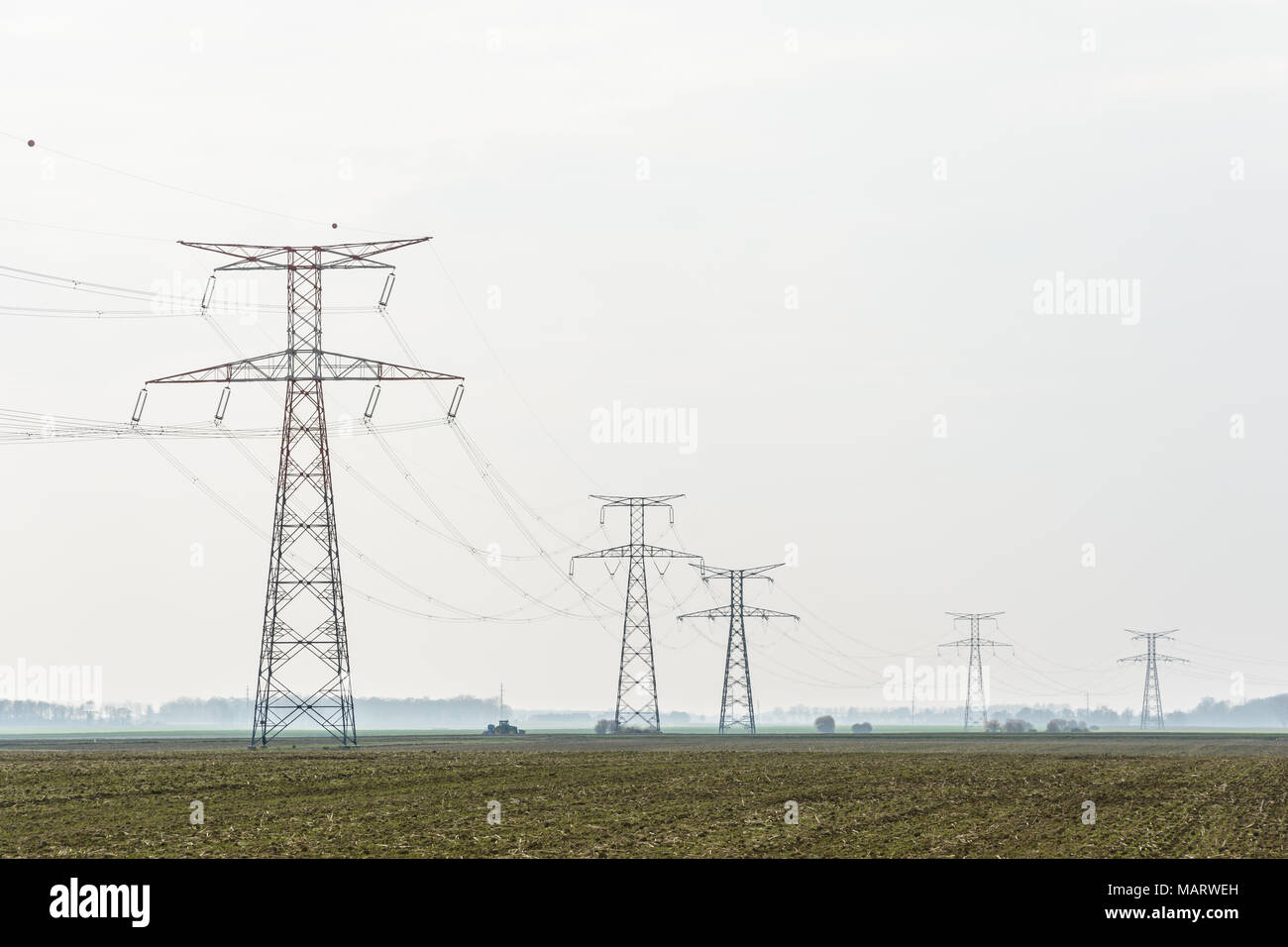 A row of transmission towers supporting a high-voltage overhead power ...