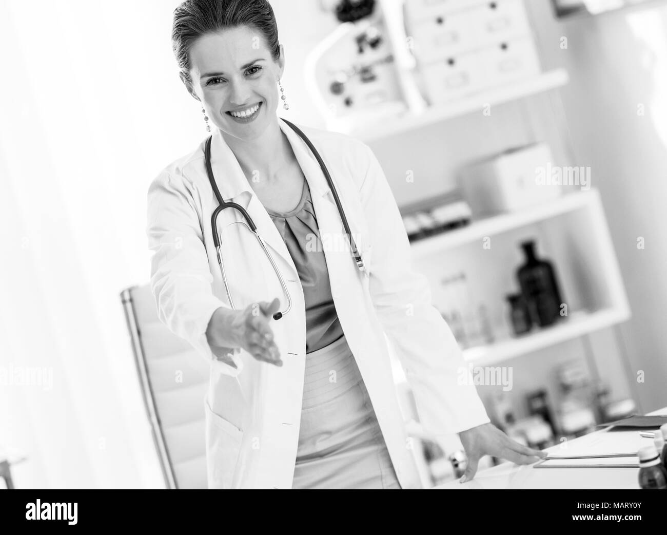 Smiling medical doctor woman in office stretching hand for handshake ...