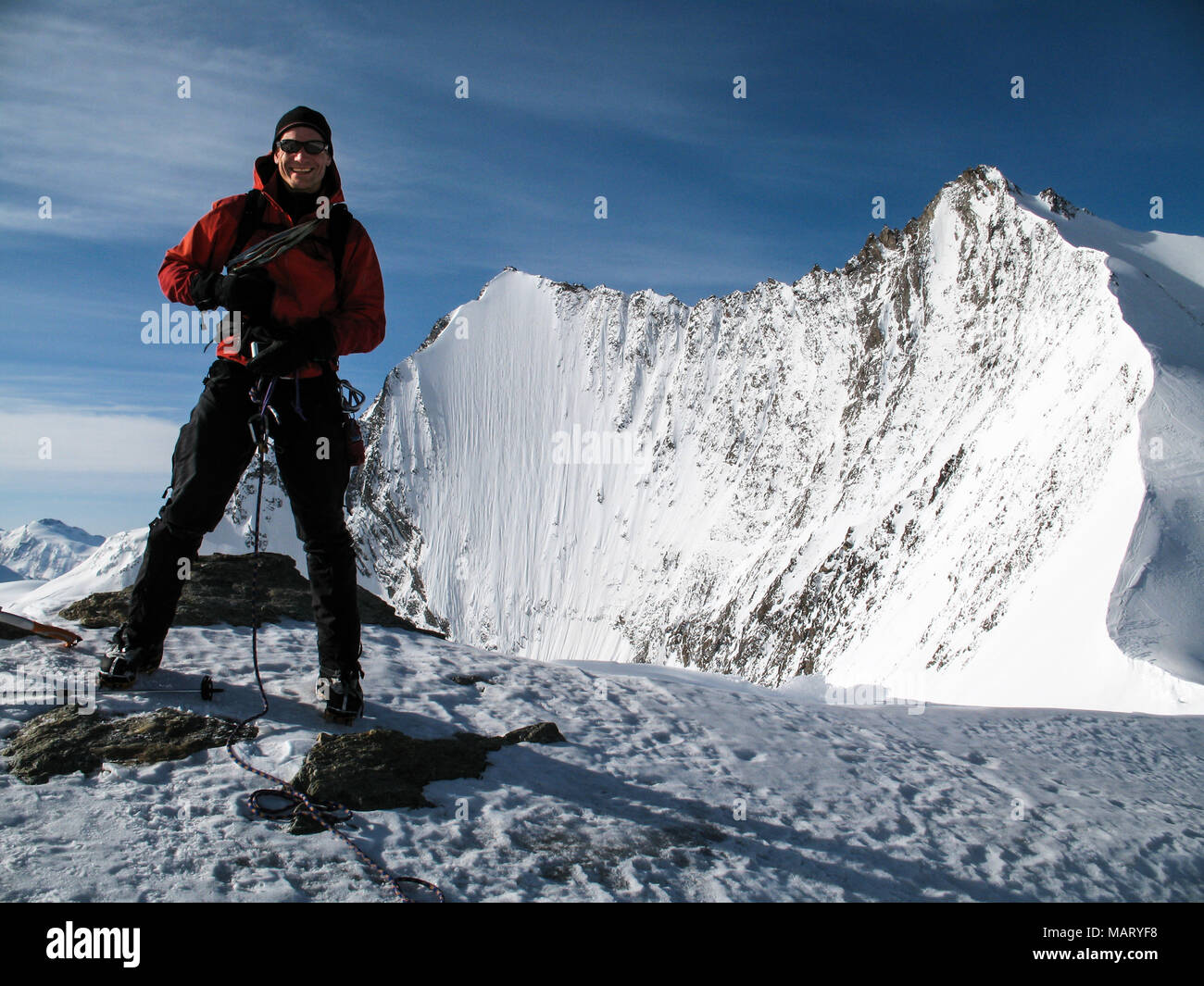 male mountain climber smiling and laughing on the summit of a high ...
