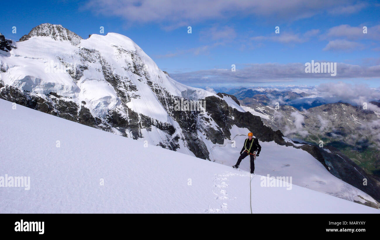 male mountain climber on a high alpine glacier with a great view of the ...