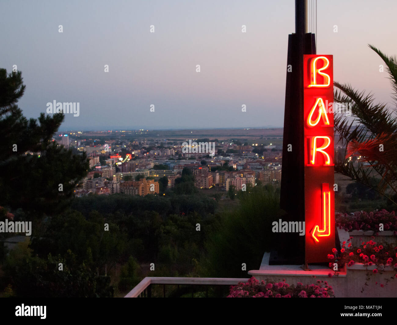 Neon lit BAR sign with arrow. Bulgaria town in the background Stock ...
