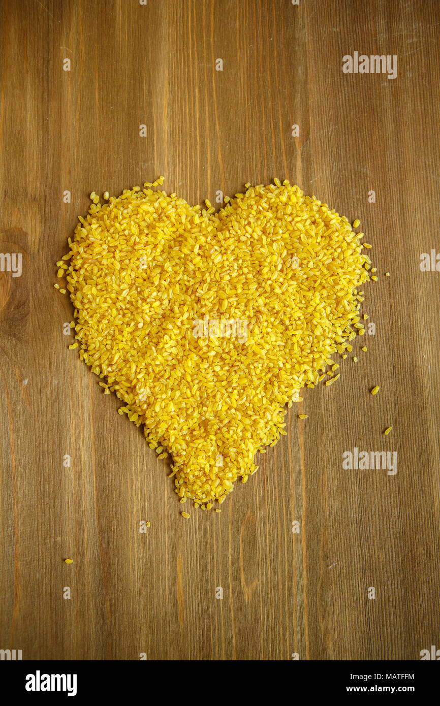Croup of bulgur placer, a pile on a wooden brown background is lined in ...
