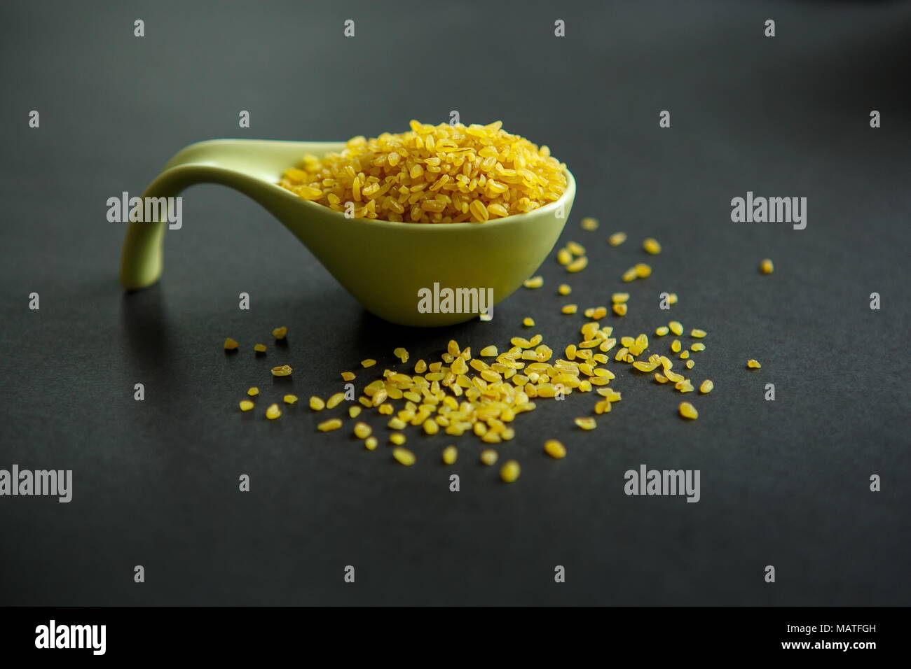 Croup of bulgur placer, pile on a black background lined in a spoon, a ...