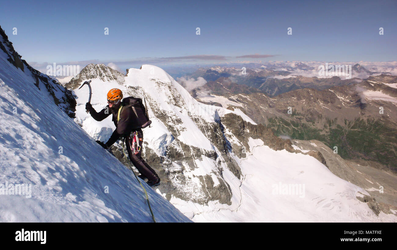 male mountain climber on a high alpine glacier with a great view of the ...