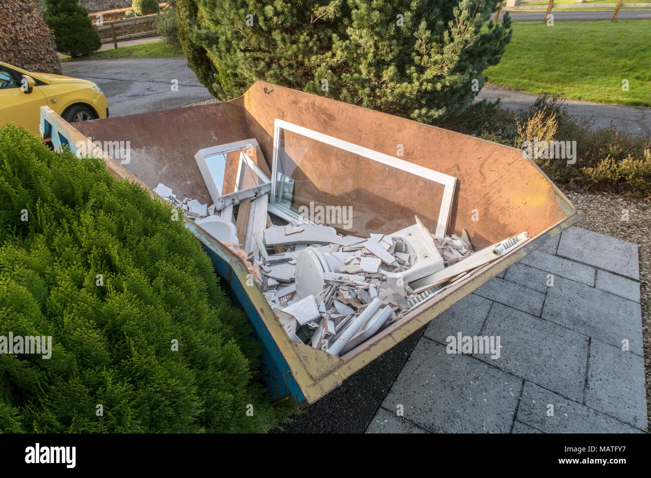 Rubbish skip on the driveway of a house, full of rubble from renovating ...