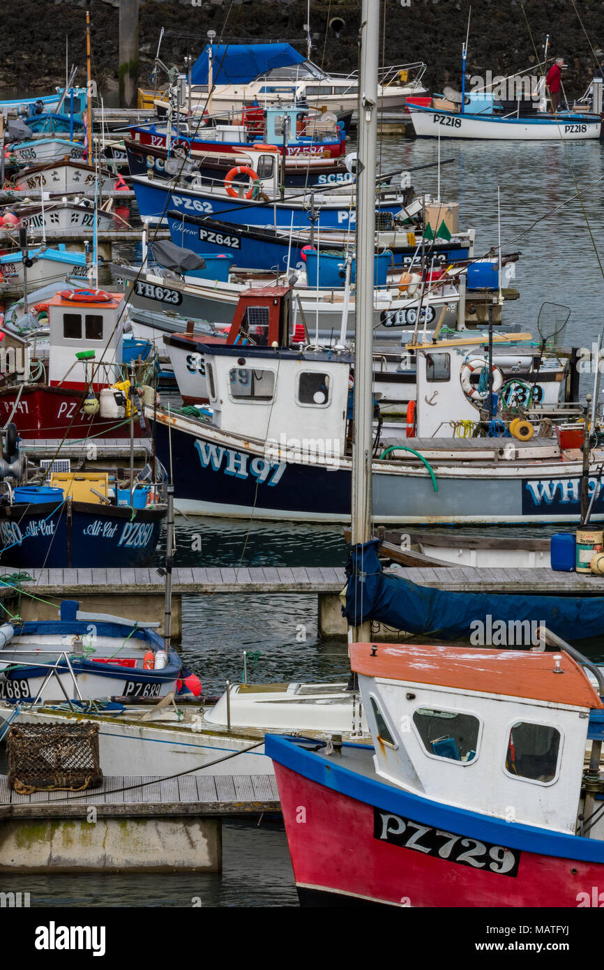 rows of fishing trawlers and boats in harbour at low tide at newlyn in ...