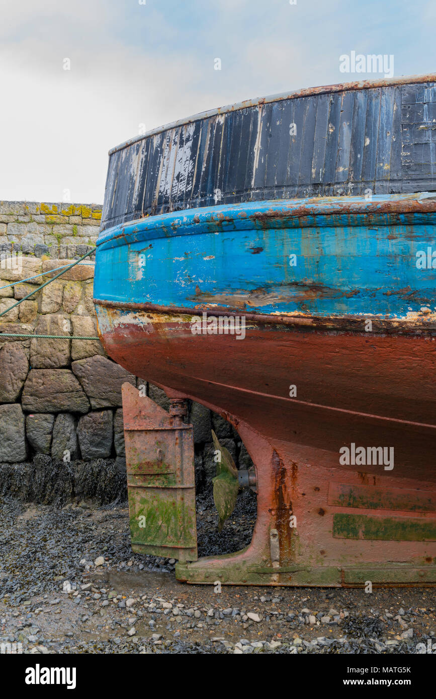 The stern of an old fishing boat left to rot and decay in a derelict ...
