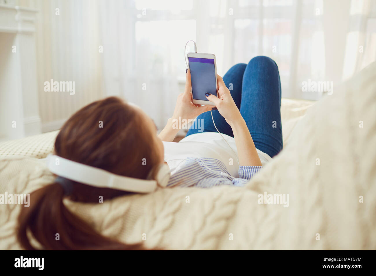 A girl in headphones looks into the phone Stock Photo - Alamy