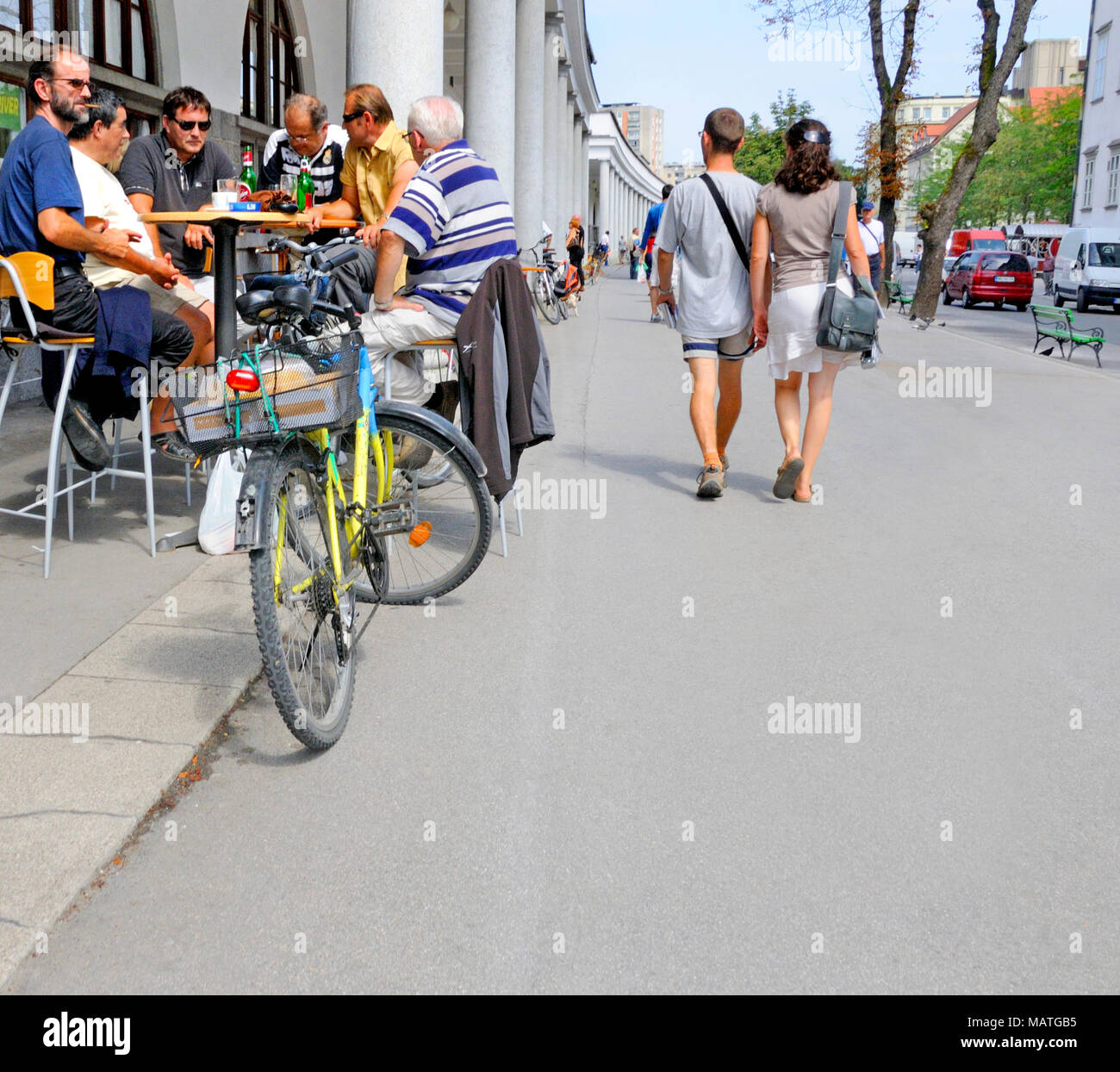 Ljubljana, Slovenia. Couple walking past men at outdoor bar table (Bar ...