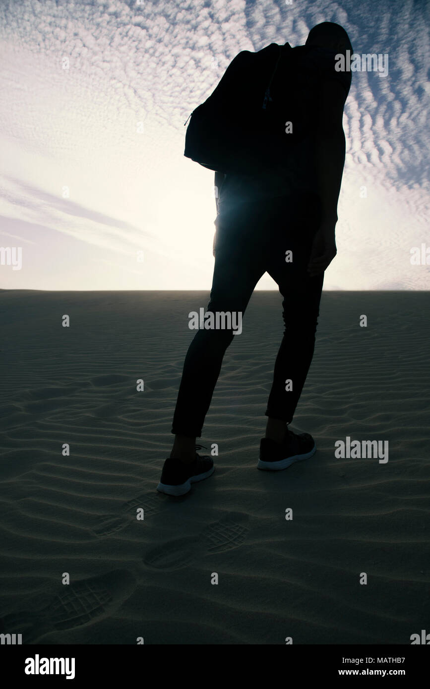 a young caucasian man seen from behind carrying a backpack, walking by ...