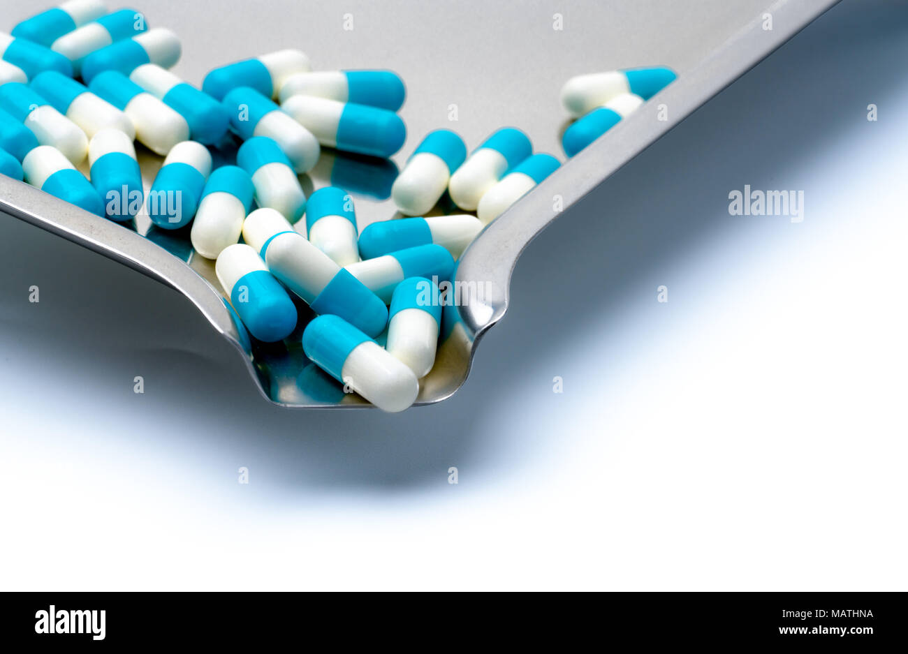 Blue and white capsules pills and drug tray on white background with ...
