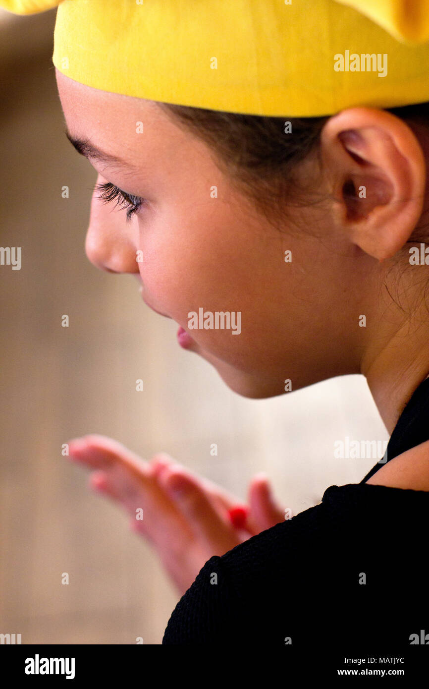 Girl in a yellow chef's cap and black apron gaily looks to the left ...