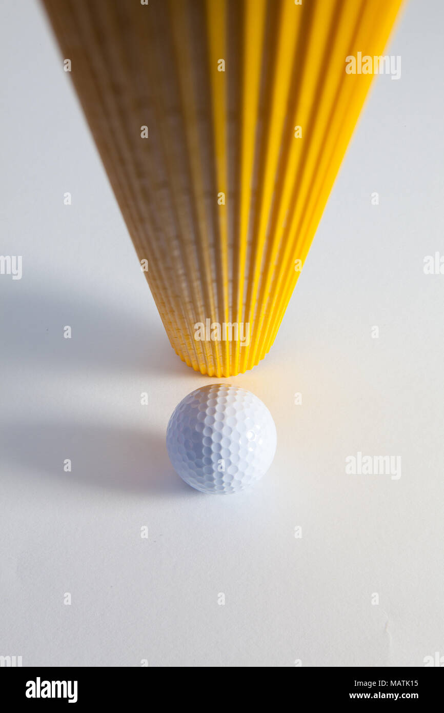 Corrugated yellow paper roll and golf ball on the white desk ...