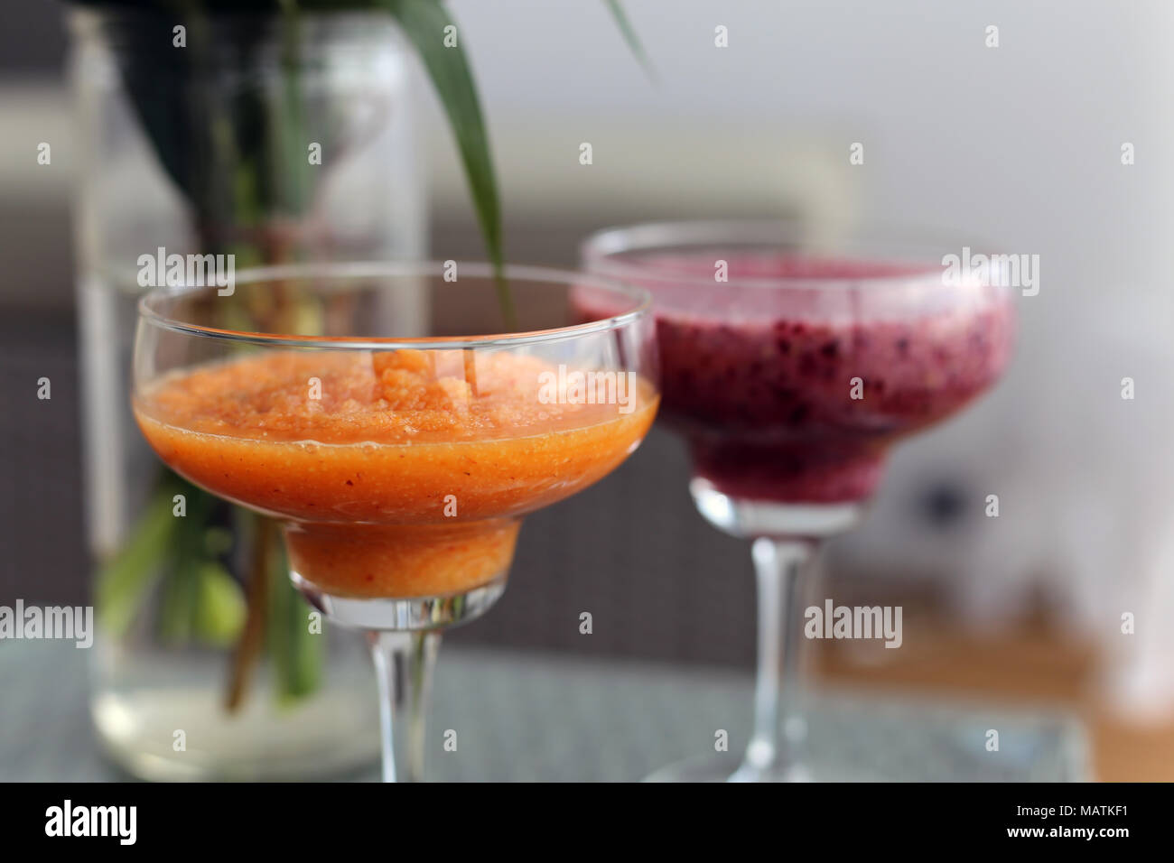 Two homemade DIY smoothies (orange and purple berry smoothie) on a ...