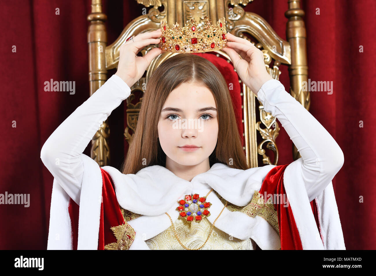 Beautiful teen girl holding crown sitting in vintage armchair Stock ...