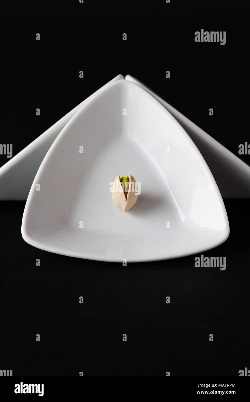 White triangular ceramic bowls with pistachio nut on the black ...