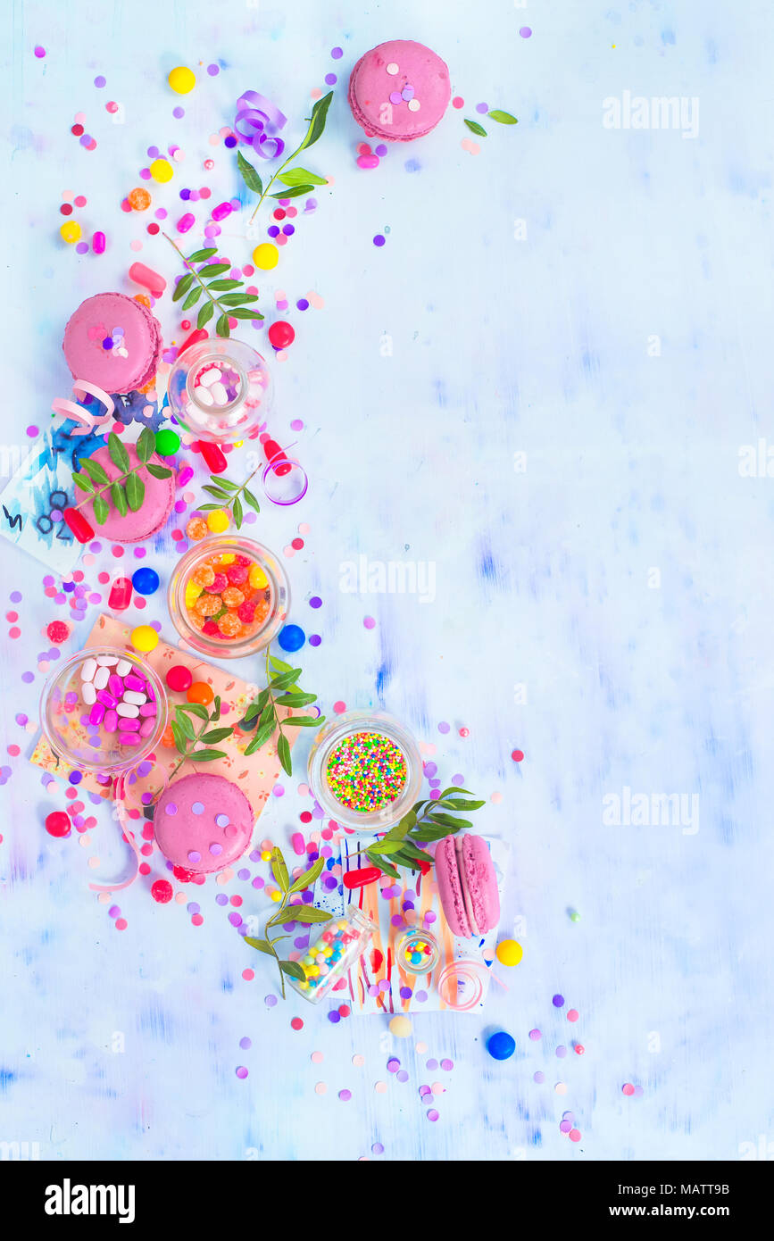 Pink macarons, candies, confetti and sprinkles in a creative party ...