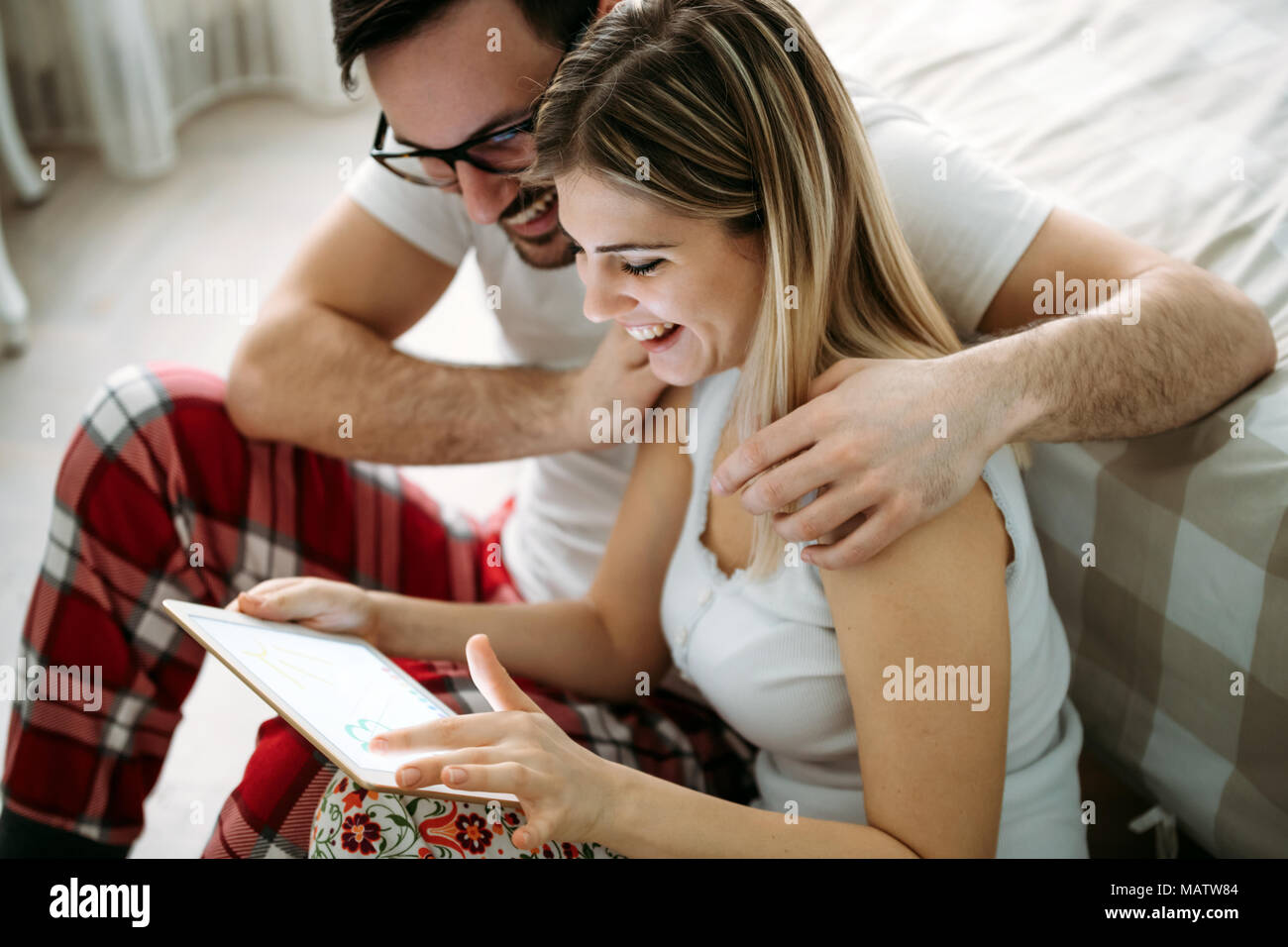 Young happy couple using tablet in bedroom Stock Photo - Alamy