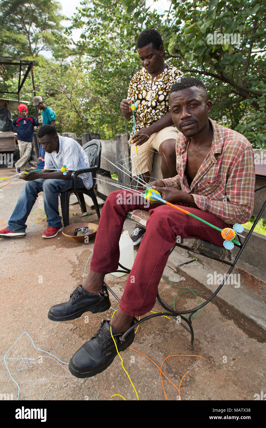 Men craft beadwork souvenirs in Harare, Zimbabwe. The men ply their ...