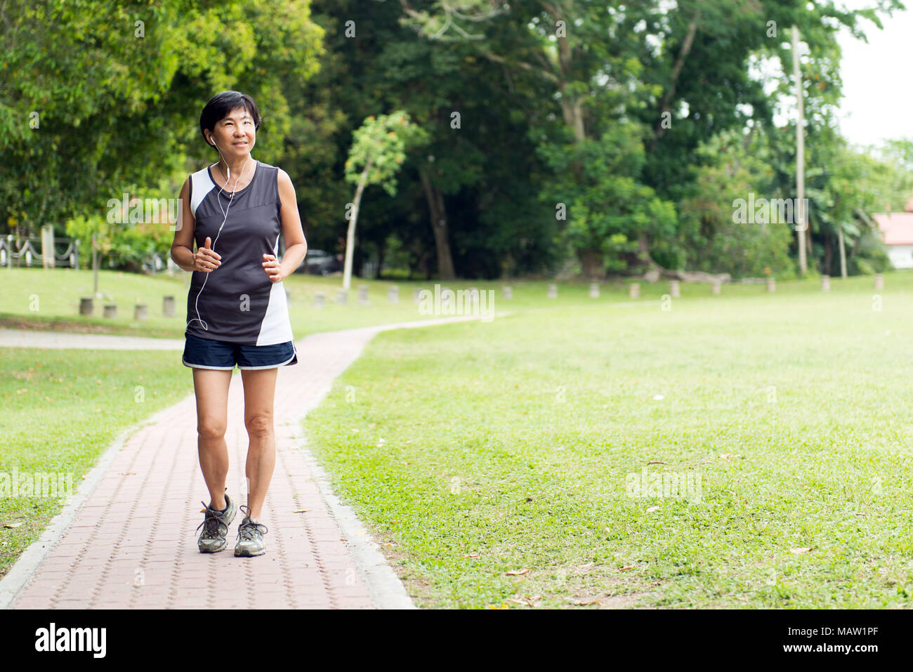 Front view of senior woman jogging through park Stock Photo - Alamy