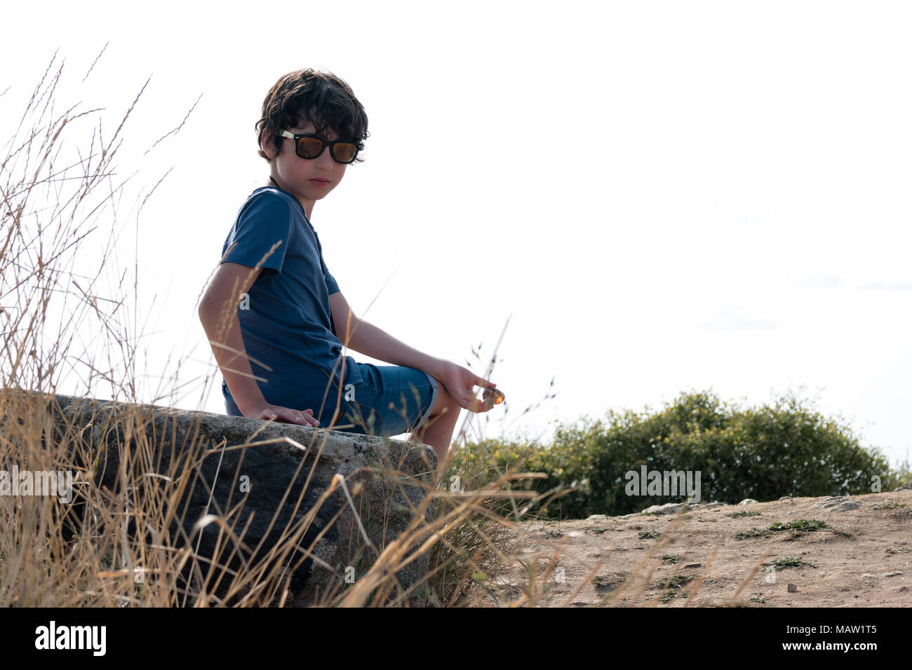 Portrait of a beautiful boy sitting on a stone Stock Photo - Alamy