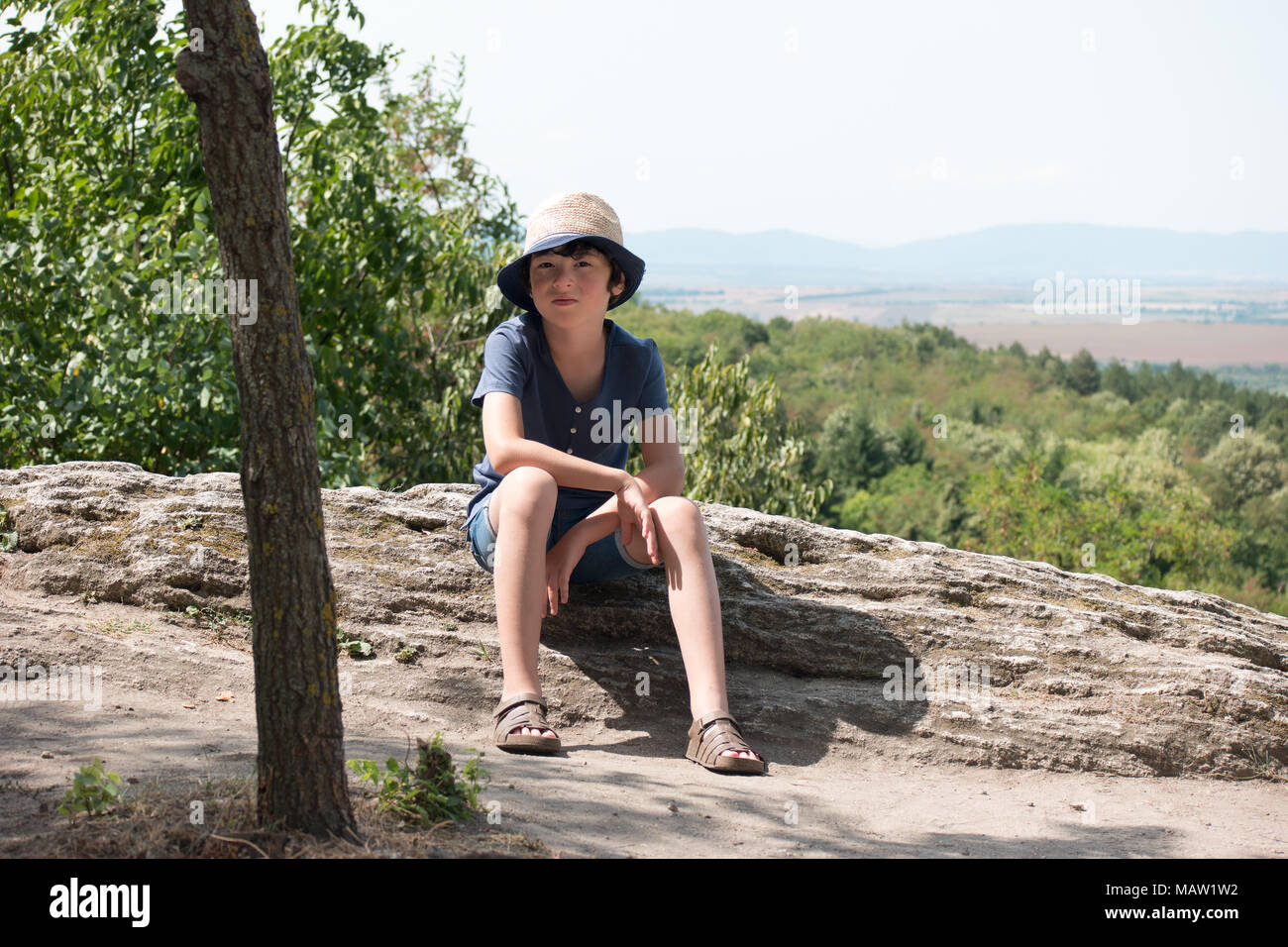 Portrait of a beautiful boy sitting on a stone Stock Photo - Alamy
