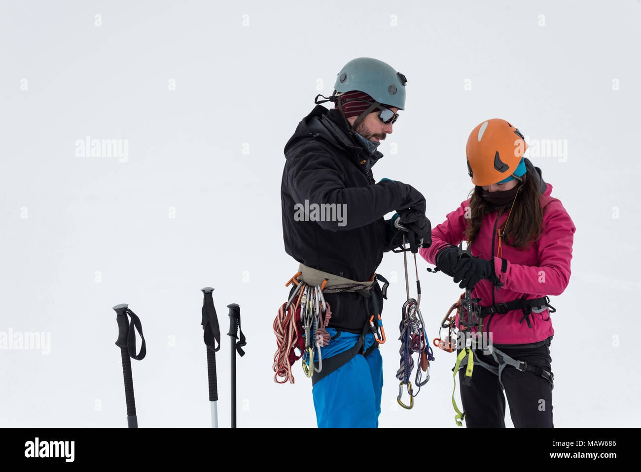 Couple wearing harness on a snow covered mountain Stock Photo - Alamy