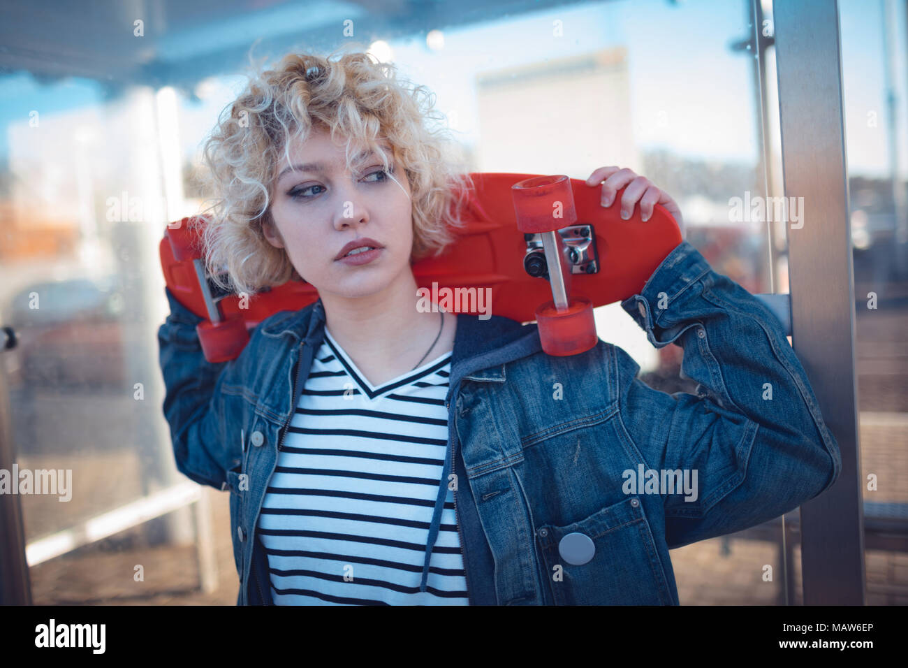 Woman holding skateboard at bus stop Stock Photo - Alamy