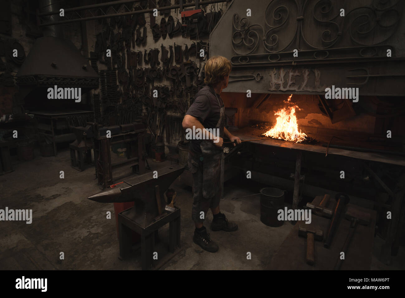 Blacksmith heating metal rod in fire Stock Photo - Alamy