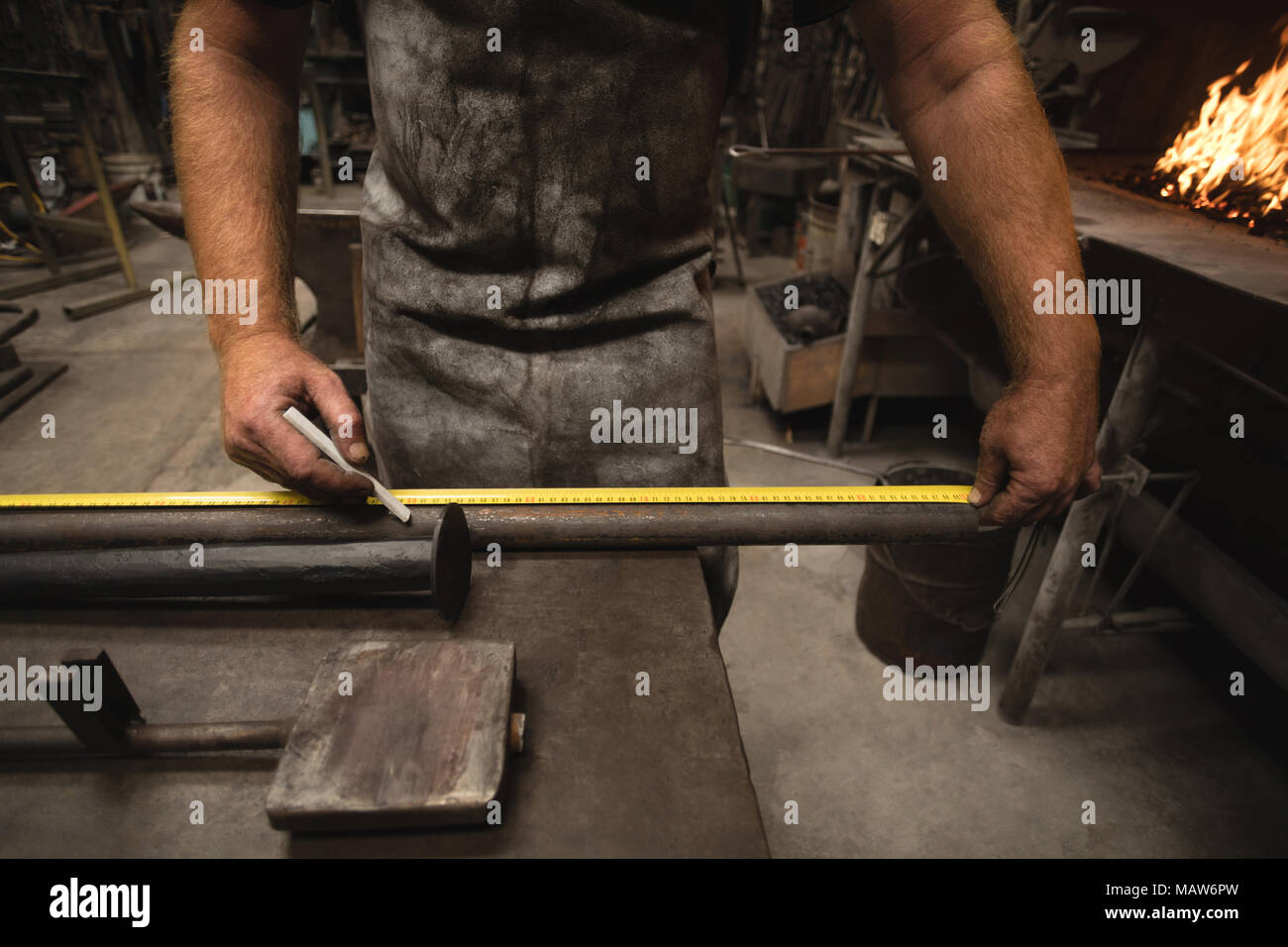 Metalsmith measuring a metal rod with measuring tape Stock Photo - Alamy