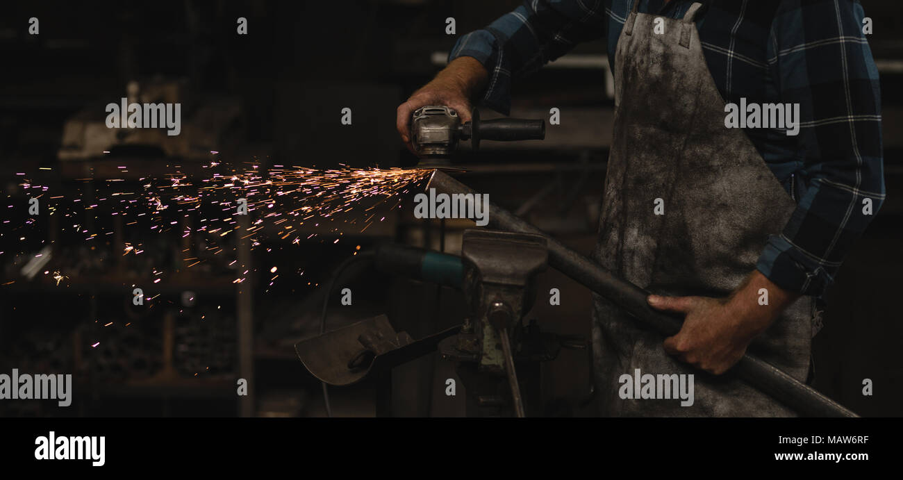 Blacksmith grinding a metal rod with grinder machine Stock Photo - Alamy