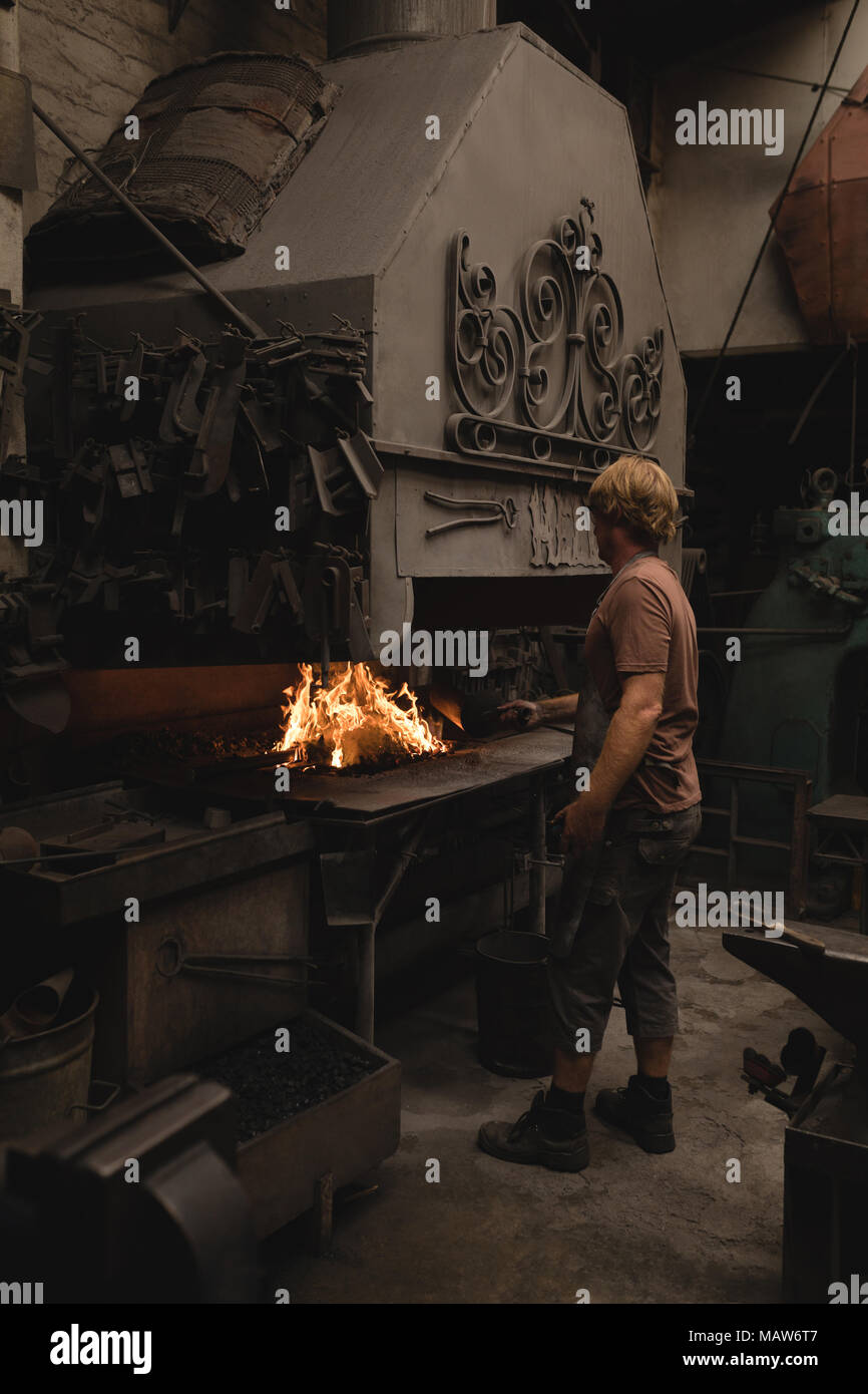 Blacksmith heating metal rod in fire Stock Photo - Alamy