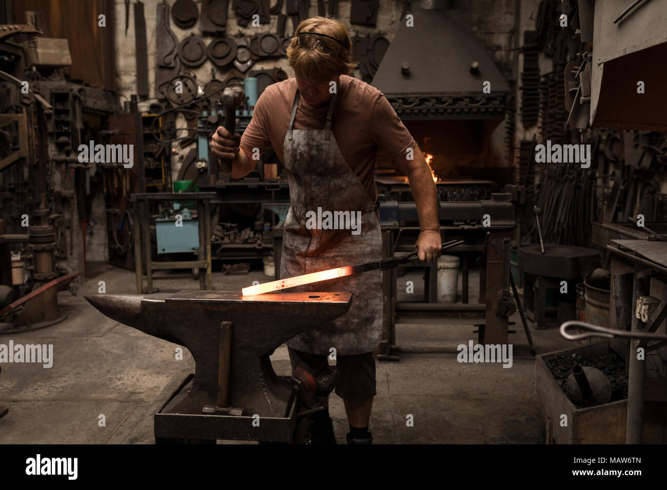 Blacksmith hammering a hot metal rod Stock Photo - Alamy