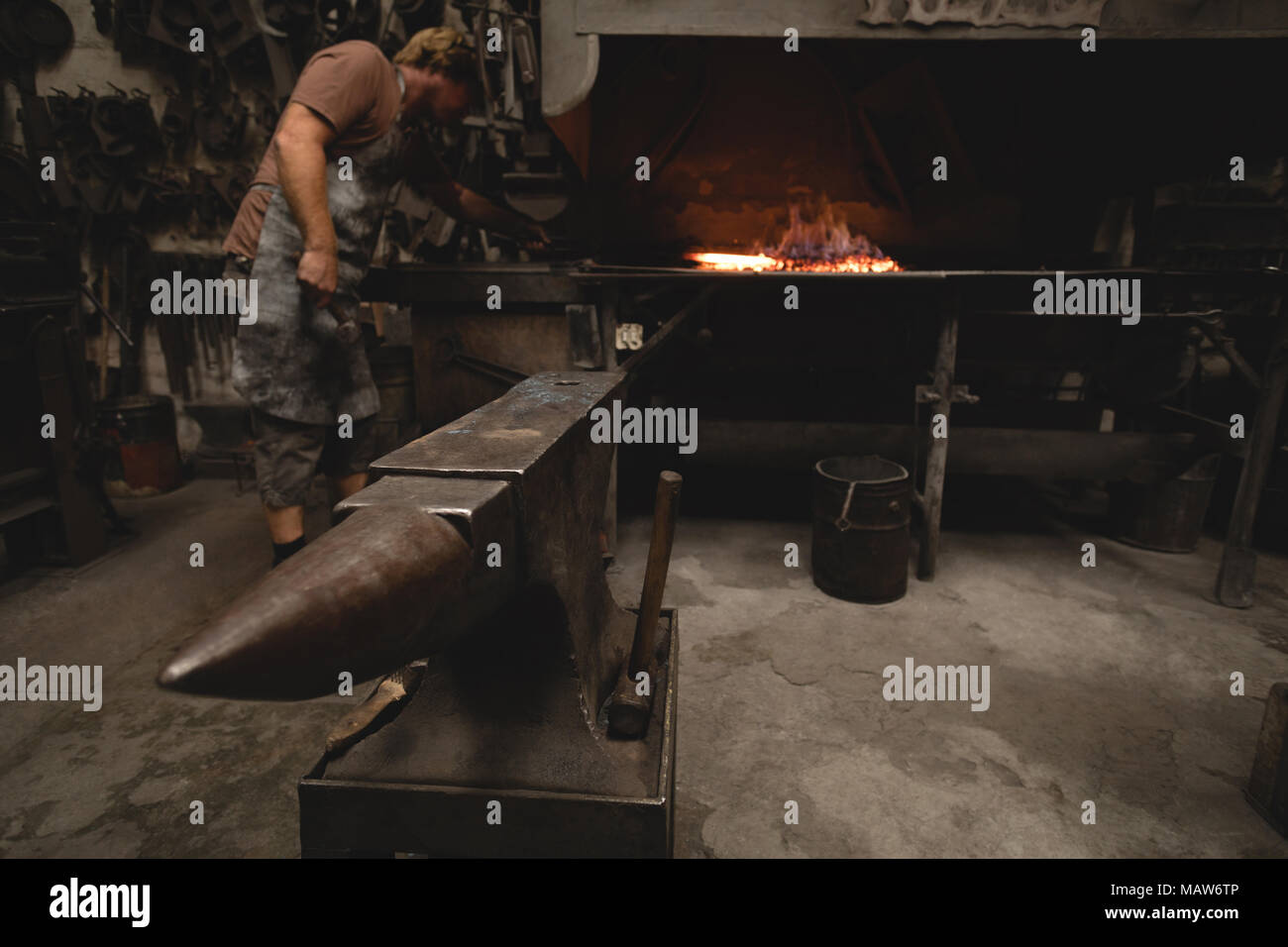 Blacksmith heating metal rod in fire Stock Photo - Alamy