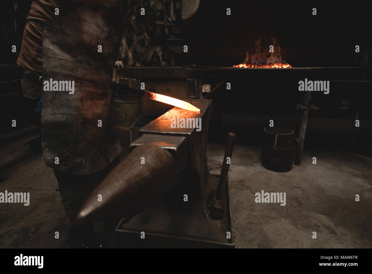 Blacksmith examining a hot metal rod Stock Photo - Alamy