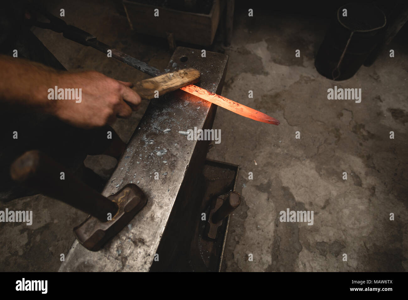 Blacksmith examining a hot metal rod Stock Photo - Alamy
