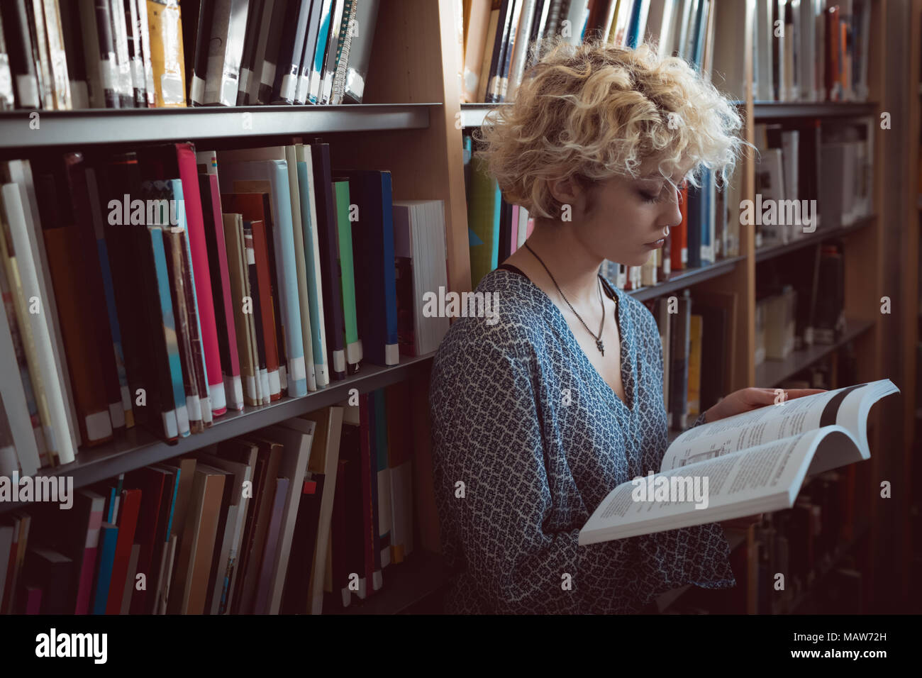 Woman reading a book in library Stock Photo - Alamy