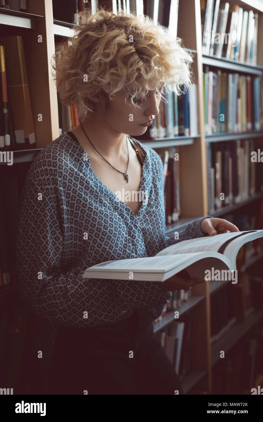 Woman reading a book in library Stock Photo - Alamy