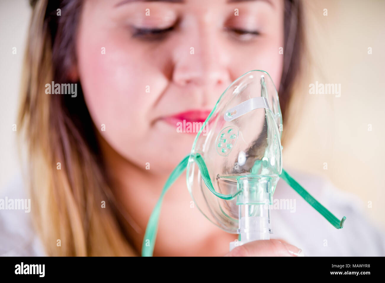 Portrait of young beautiful woman using nebulizer for asthma and ...