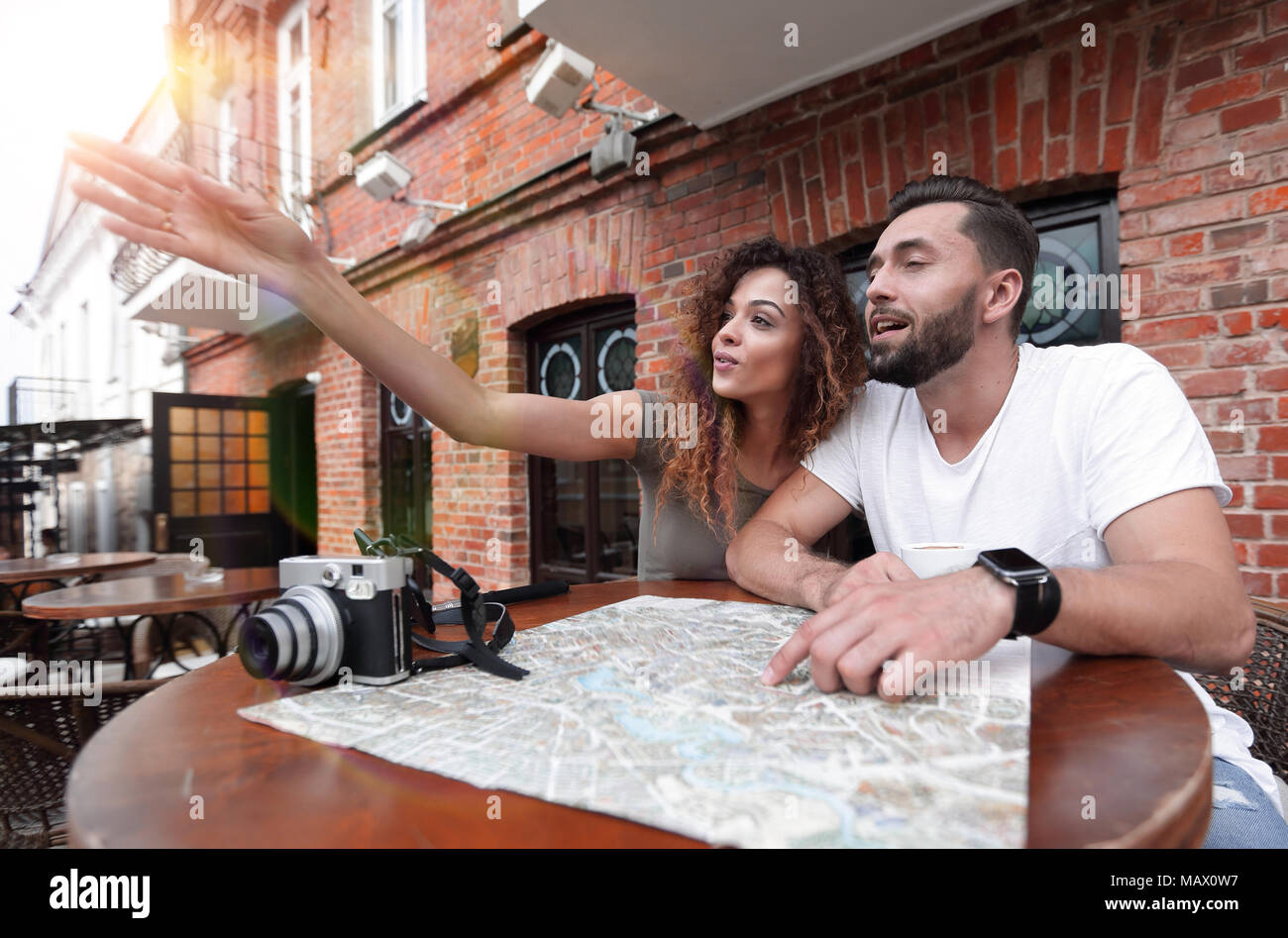 Young tourists drinking coffee at cafe and reading city map Stock Photo ...