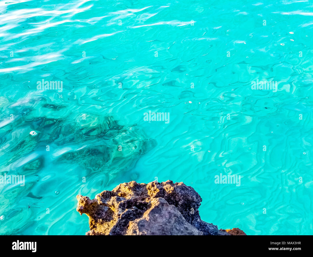 Turquoise blue clean clear water and rocks on the shoreline in Turks ...