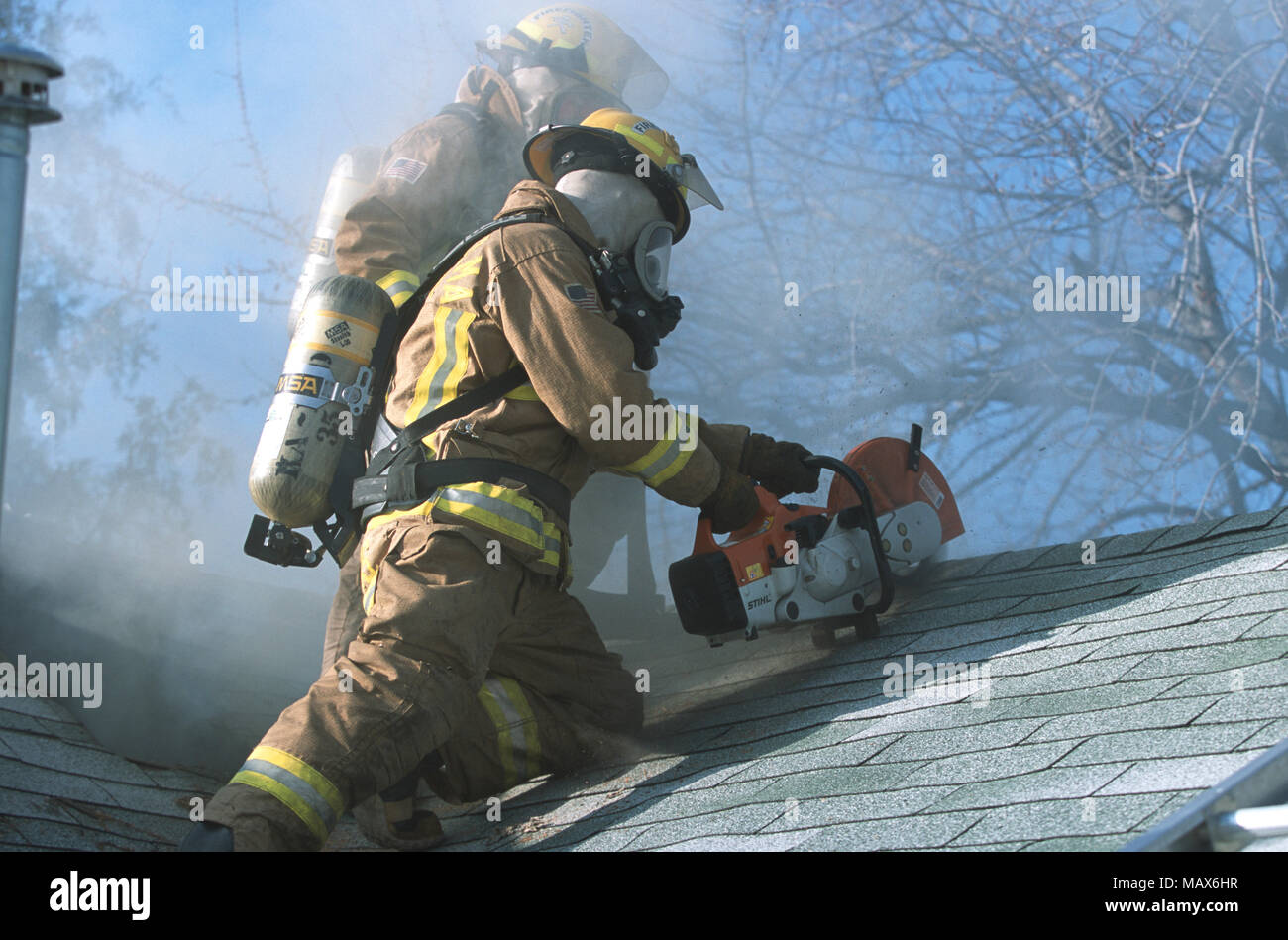 63818-01606 Firefighter using saw to ventilate smoke from house fire ...