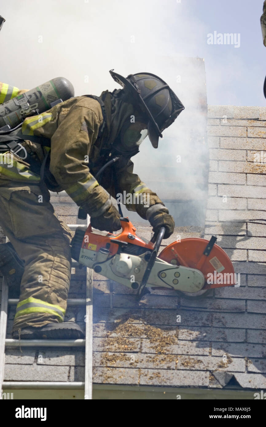 63818-019.04 Firefighter cutting hole in roof for ventilation at house ...