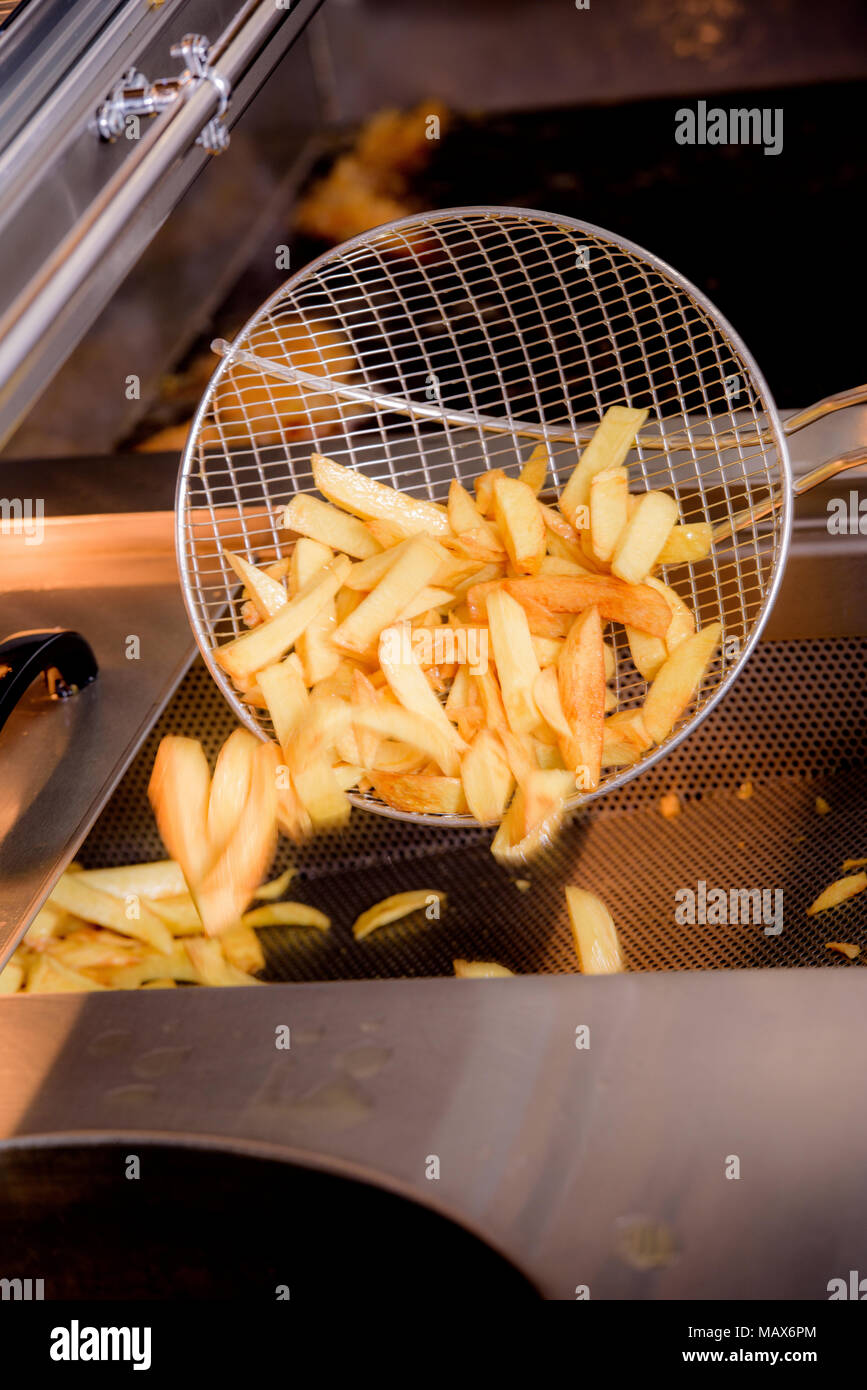 A basket of freshly cooked chips are thrown into the dryer and ready ...