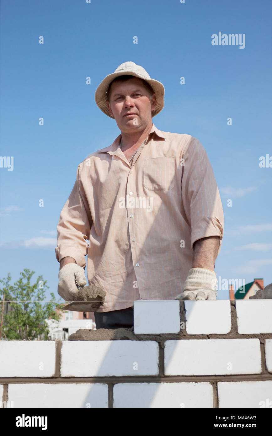 Bricklayer builds a wall of white brick Stock Photo - Alamy