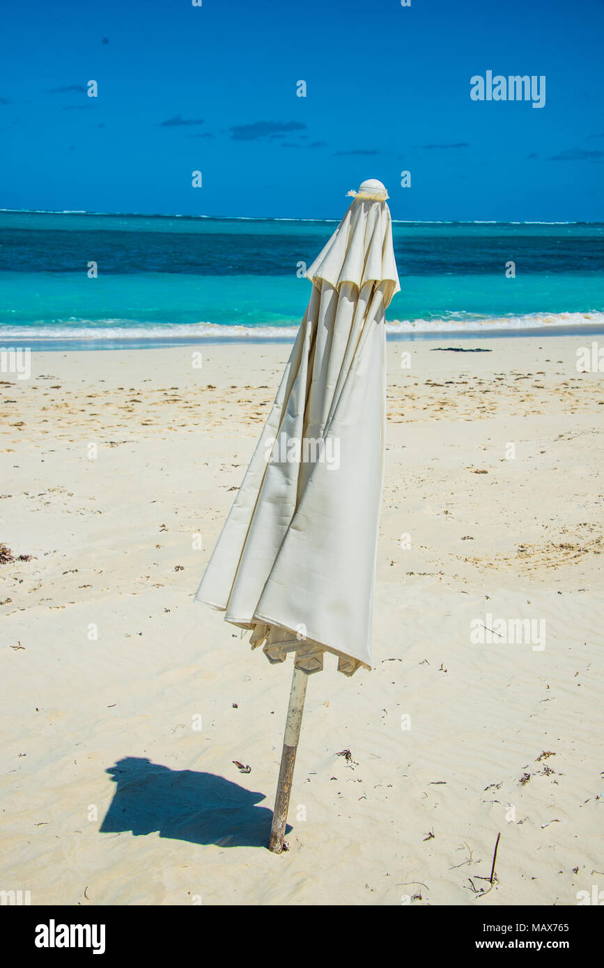 Beach umbrella on a golden tropical beach with calm blue ocean on the ...