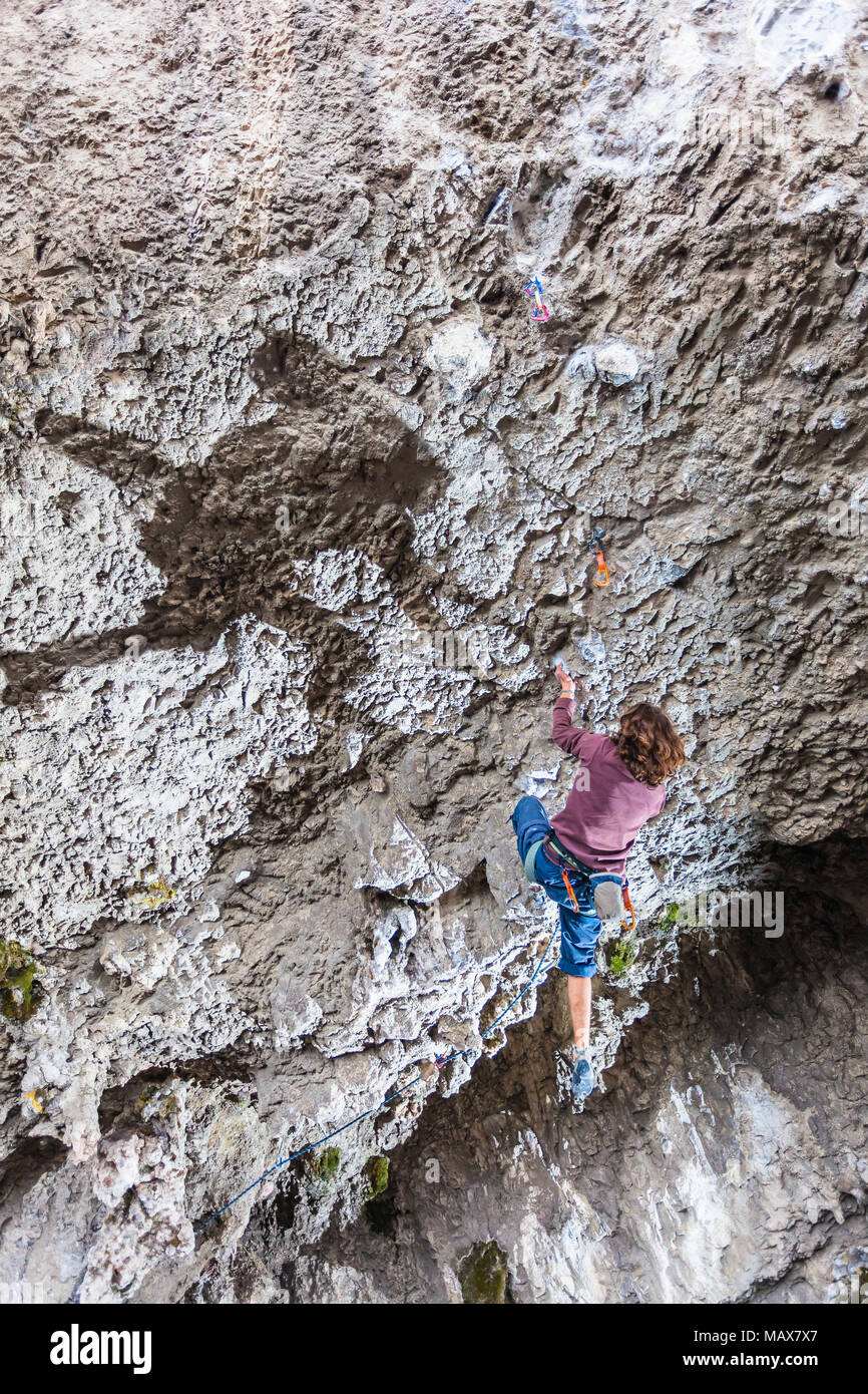 Spectacular shadow of Young climber climbing the rock walls of a cave ...