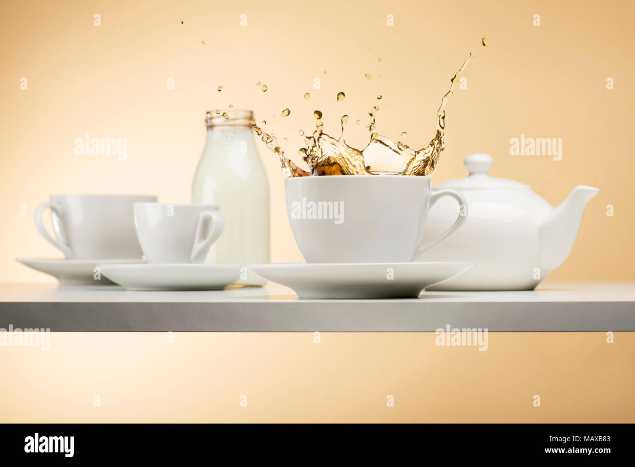 cap of tea on white table with splashing tea Stock Photo - Alamy